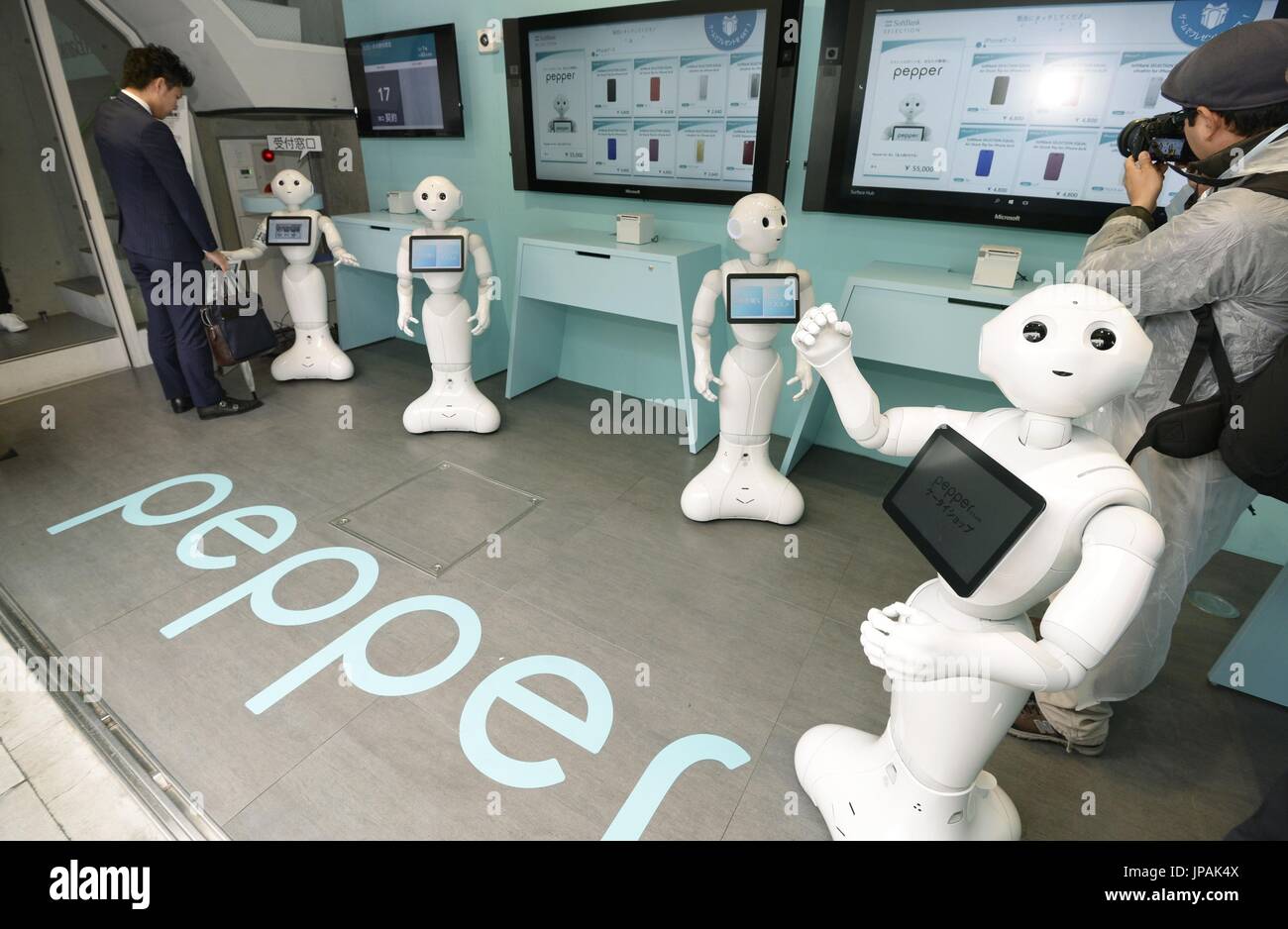 Photo taken March 24, 2016, shows Pepper humanoid robots taking care of customers at a newly ...