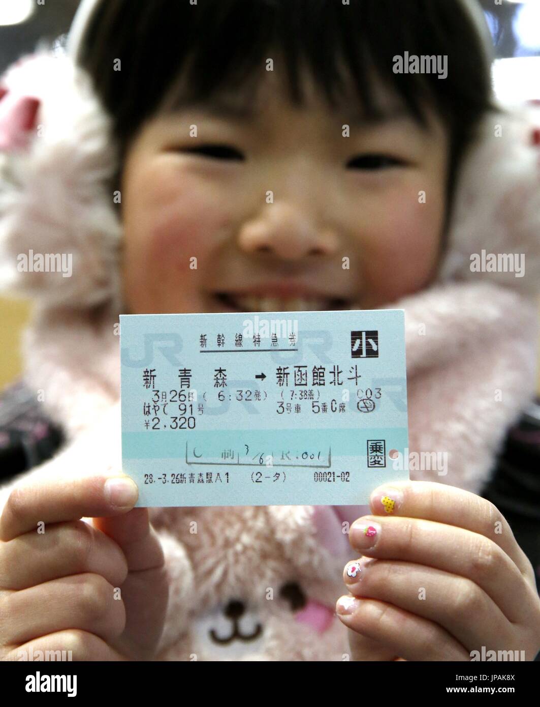 A little girl smiles with her shinkansen bullet train ticket while ...