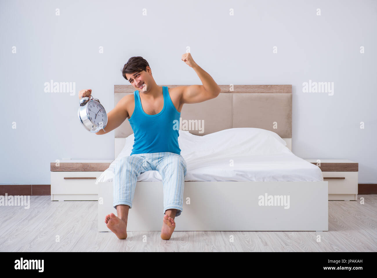 Young man waking up in bed Stock Photo - Alamy