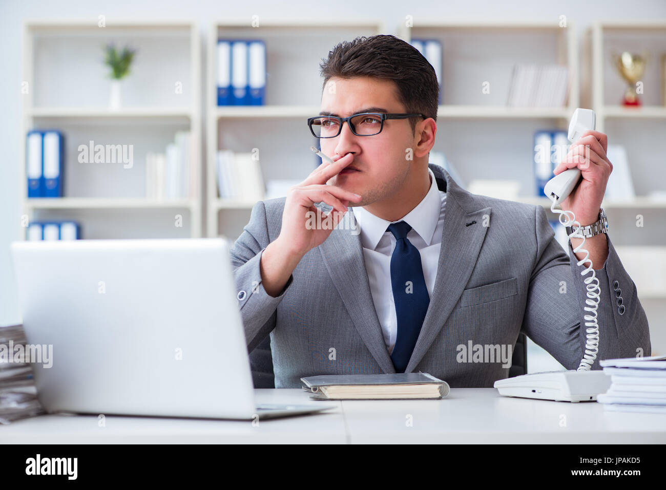 Businessman smoking in office at work Stock Photo - Alamy