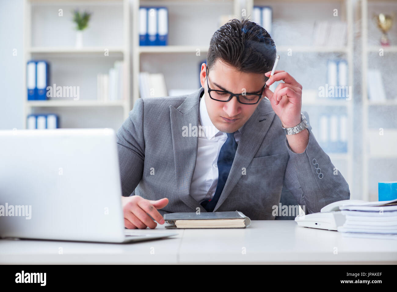 Businessman smoking in office at work Stock Photo - Alamy