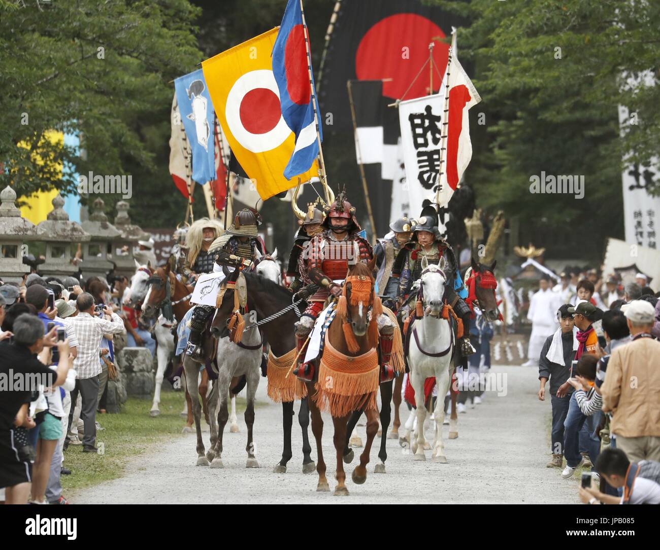 Men dressed as armed warriors leave a shrine in a traditional parade in ...