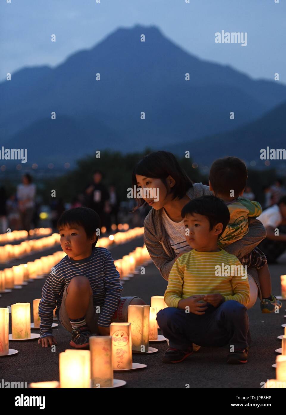 A woman and her children look at candles in Shimabara, southwestern ...
