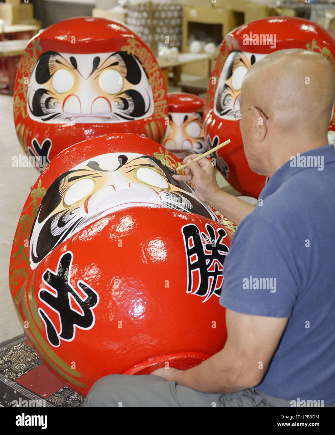 A craftsman of the Japanese traditional "daruma" doll paints the word ...