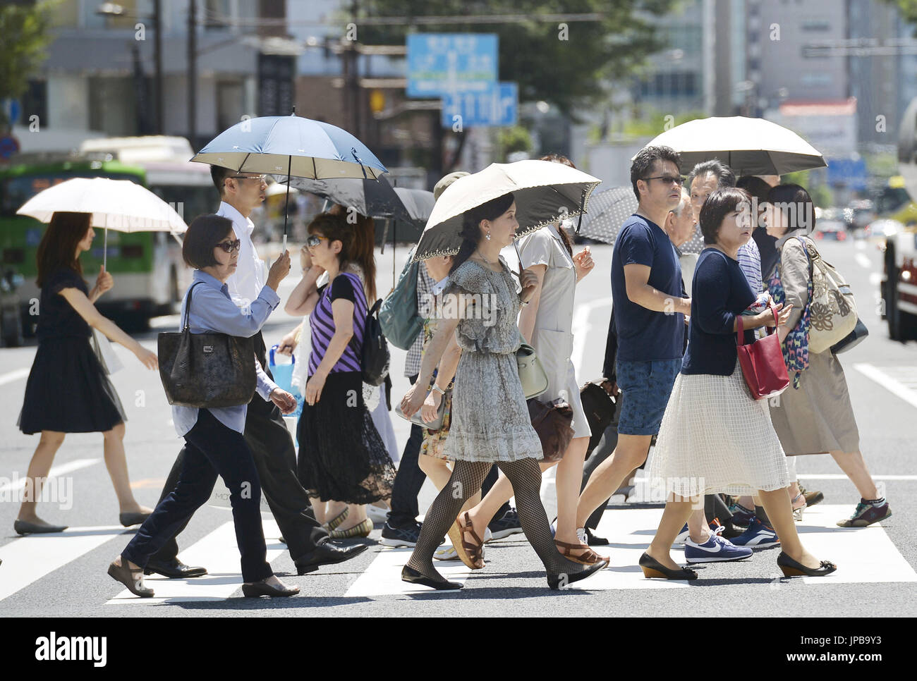 People walk in Tokyo's Ginza shopping district with parasols on June 18 ...