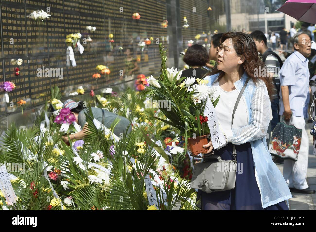 A woman lays flowers at the Tangshan earthquake memorial wall in ...