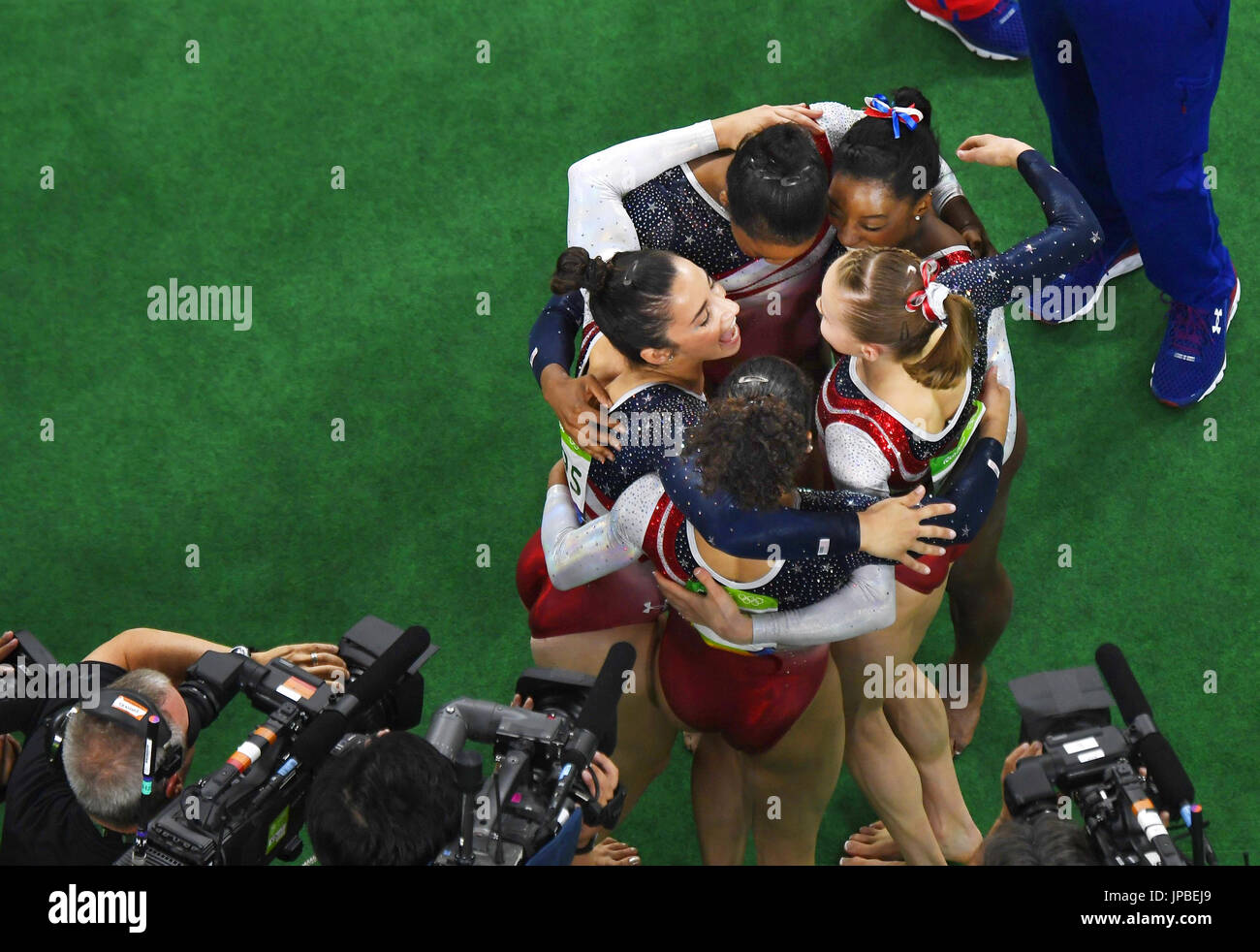 Five U.S. gymnasts hug in a ring of joy after winning gold in the women ...