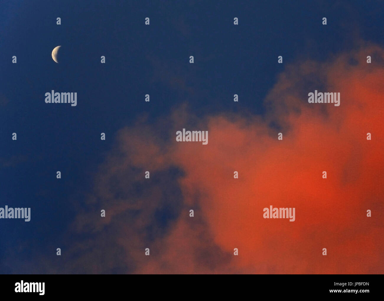 Sickle moon in front of cloud in the evening light Stock Photo - Alamy
