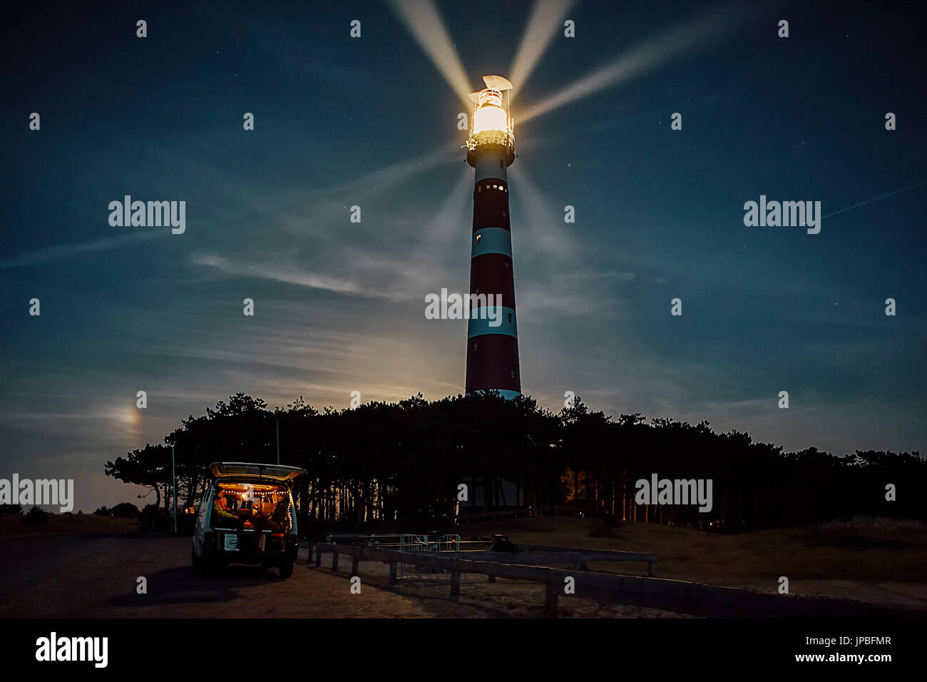 A car in front of the Lighthouse on Ameland island by night, moon rises ...