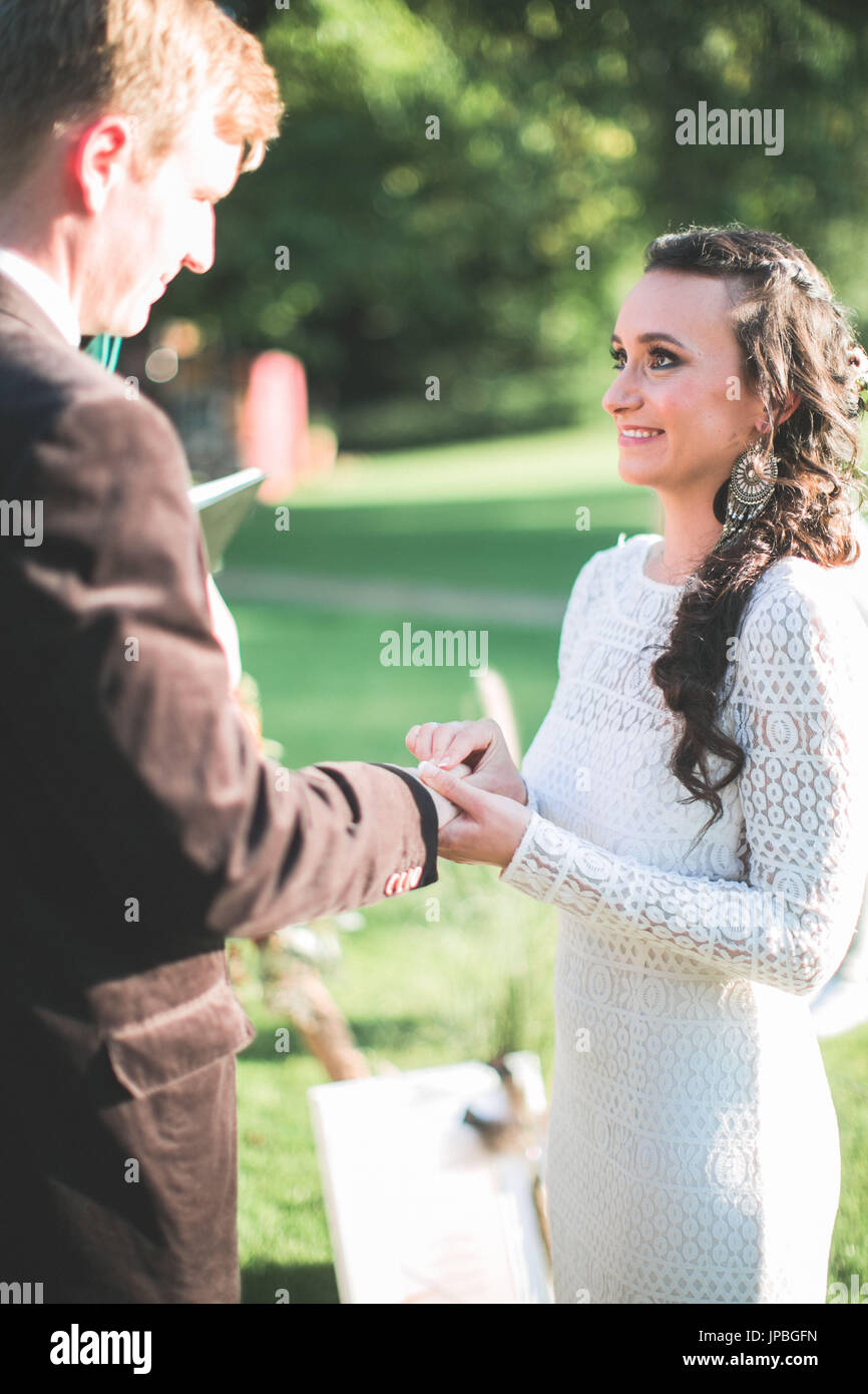 Alternate bridal couple at wedding ceremony outdoors, half profile ...