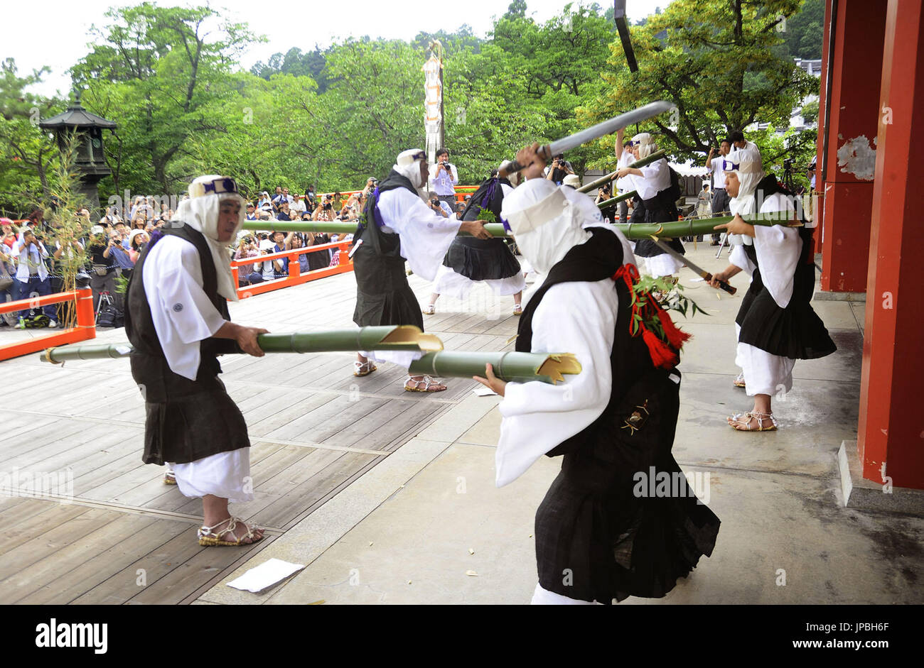 Men dressed as armed priests hack down green bamboo logs, representing ...