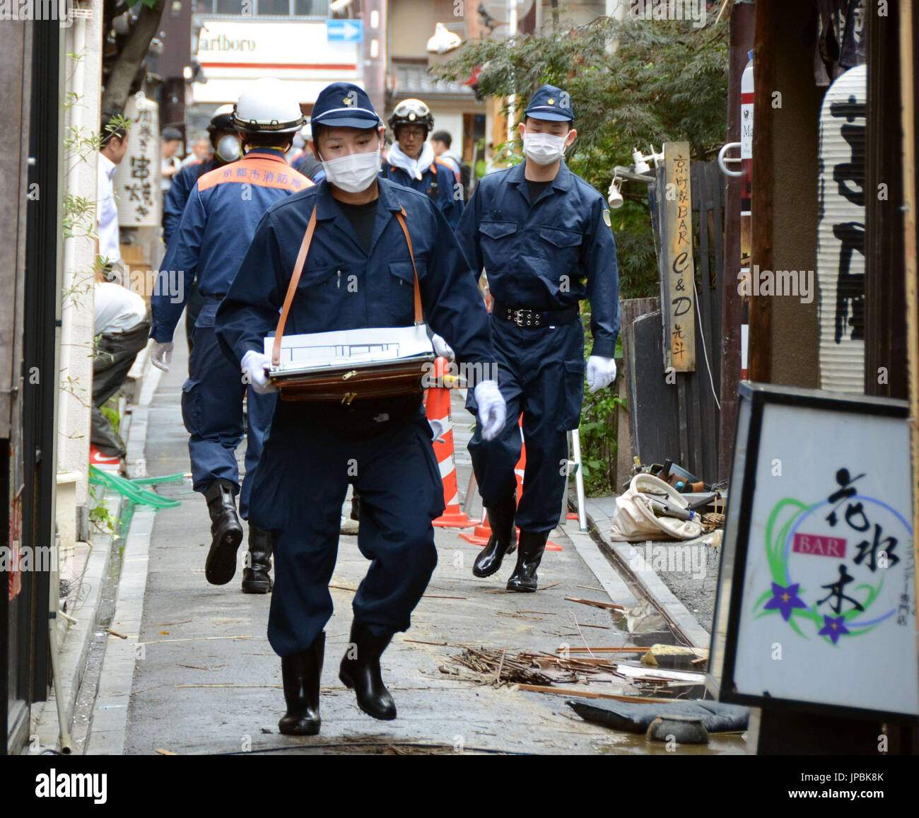 Police and firefighters inspect the scene of a fire at the Pontocho ...