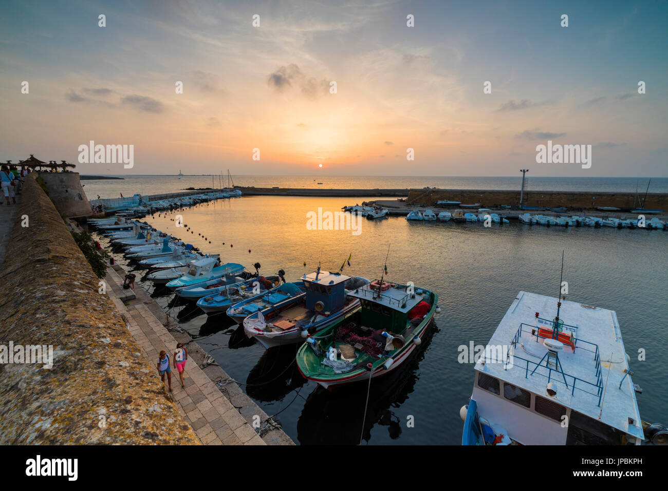 Sunset lights on boats moored in the harbor surrounded by medieval ...
