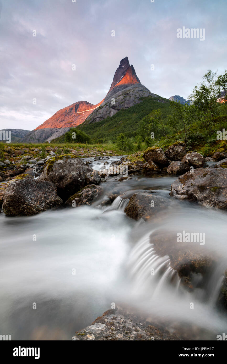 Waterfall frames the Stetinden mountain peak illuminated by midnight ...