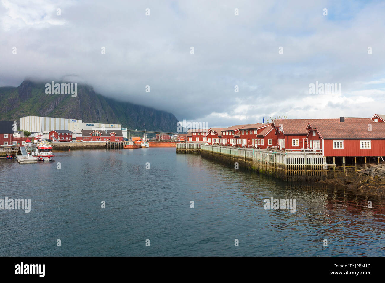 Clouds on rocky peaks frame the typical rorbu of fishing village ...
