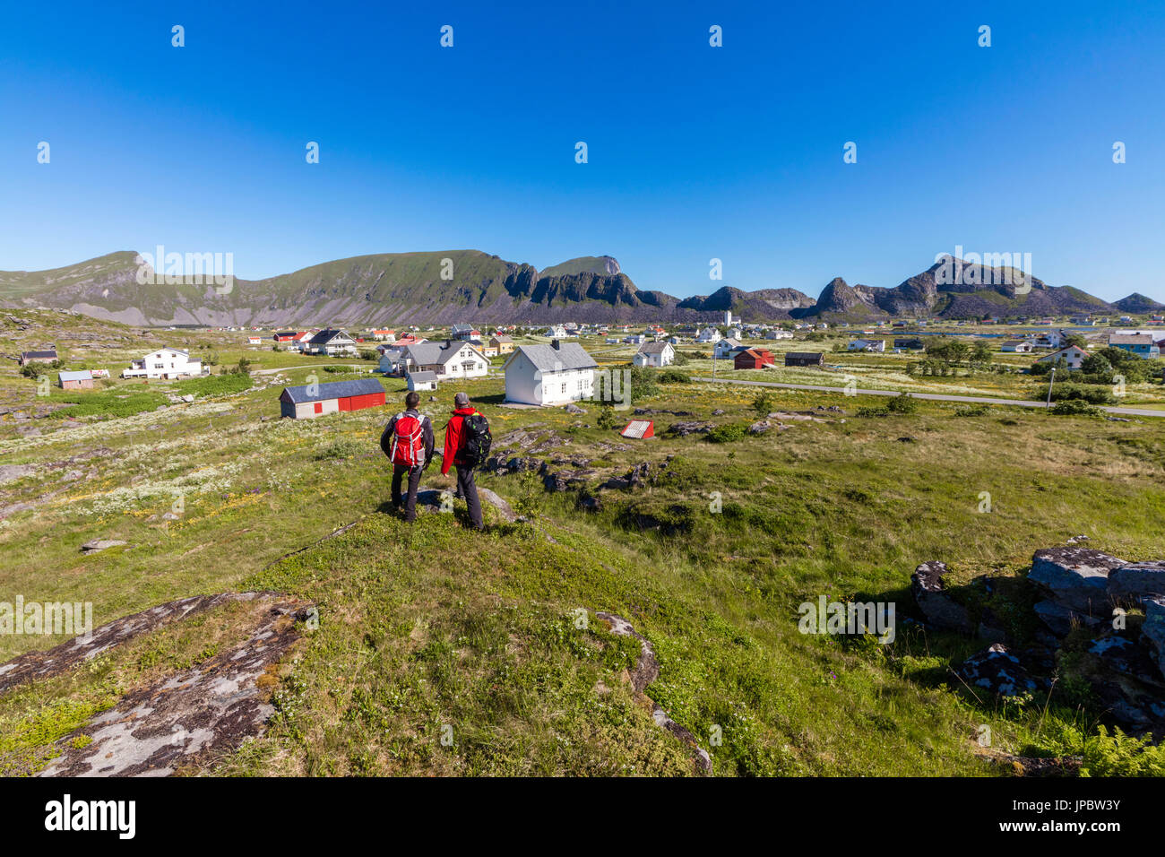 Hikers admire the village of Sorland surrounded by green meadows Vaeroy ...
