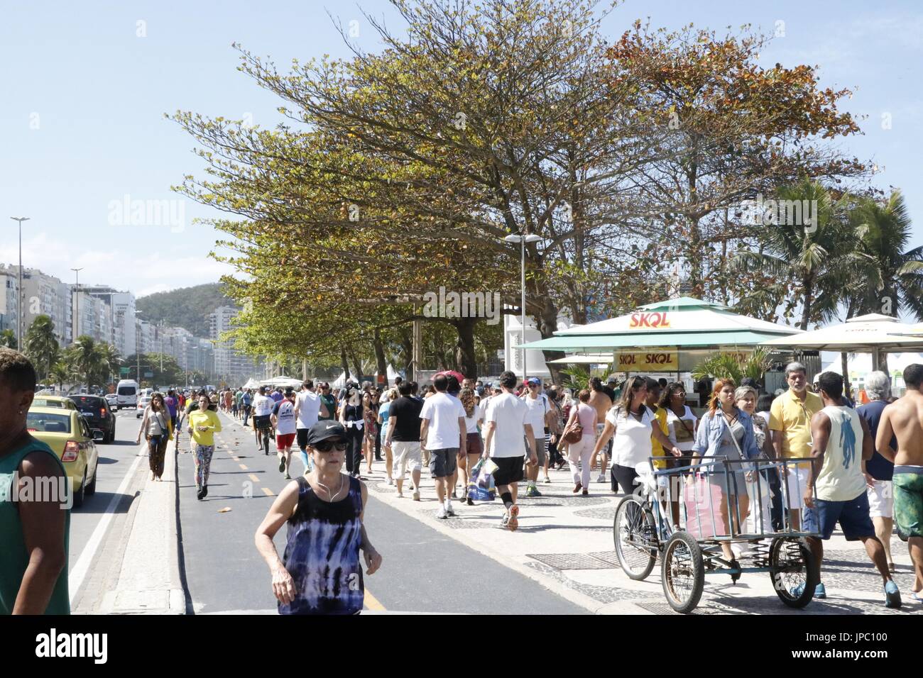 Hordes of people stroll down the iconic Copacabana promenade alongside ...
