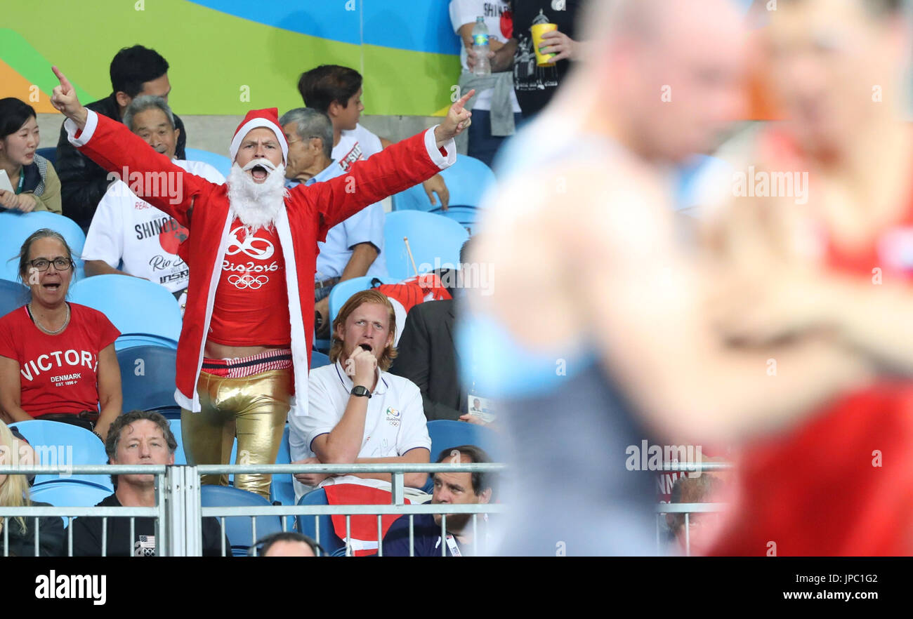 A spectator wearing a Santa Claus costume and golden trousers cheers ...