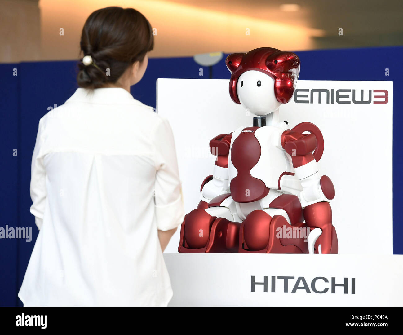 EMIEW3, a humanoid robot developed by Hitachi Ltd., guides a passenger ...