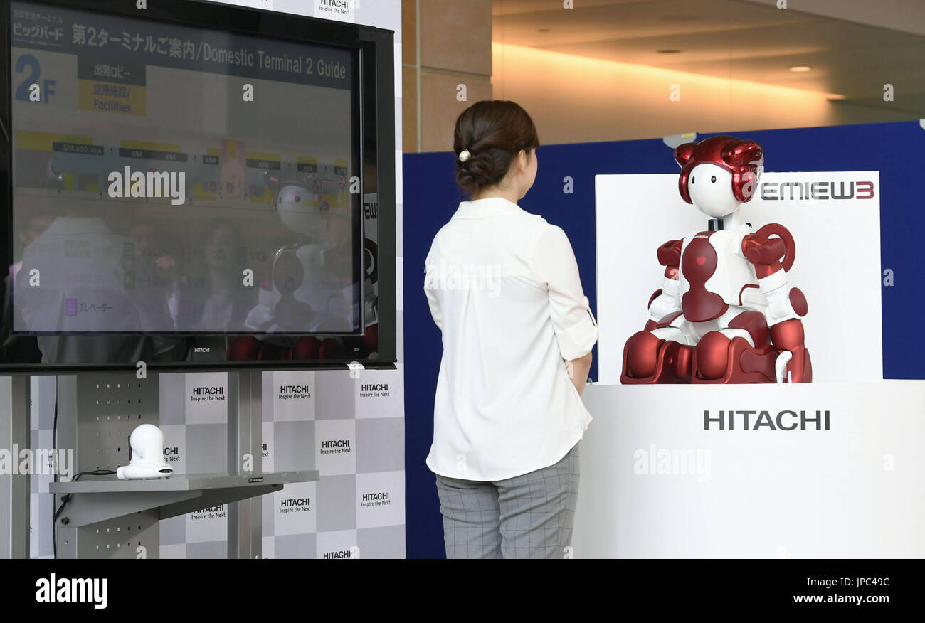 EMIEW3, a humanoid robot developed by Hitachi Ltd., guides a passenger ...
