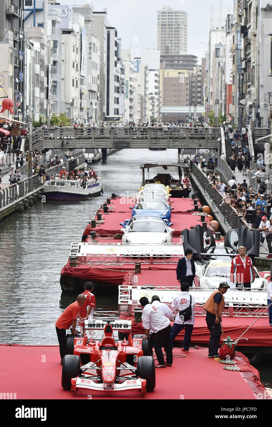 People watch a parade of Ferrari sports cars along a river in Osaka on ...