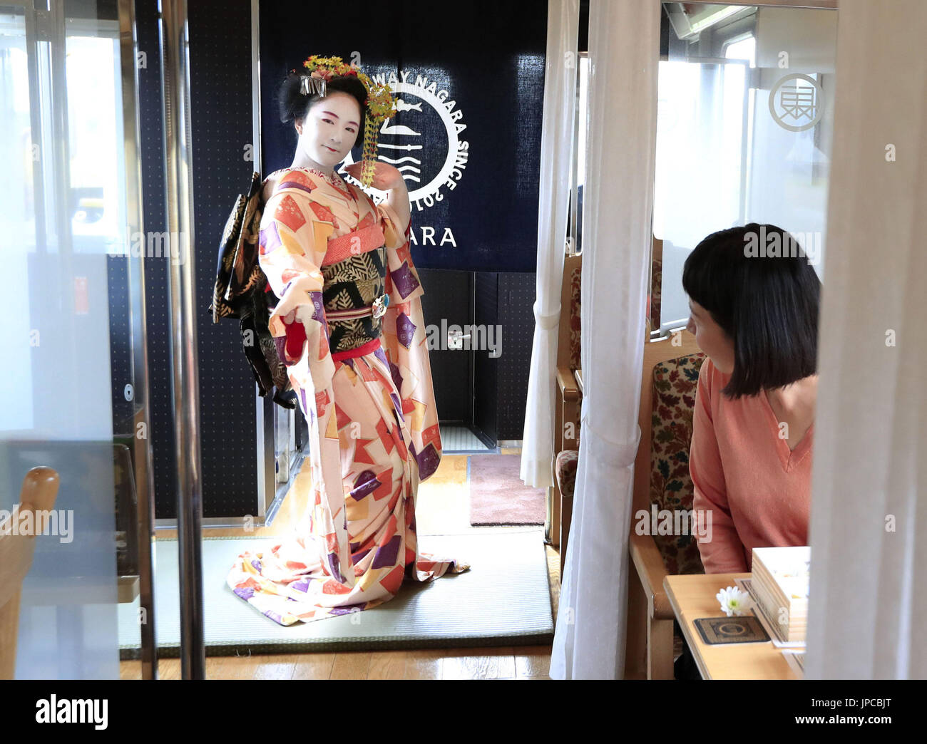 A geisha gives a preview of a dance performance inside a train carriage ...