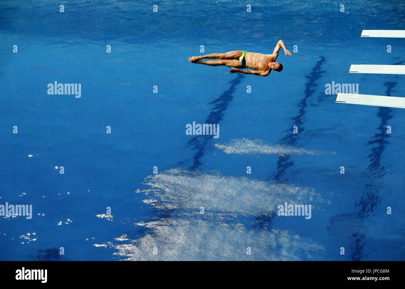 A Brazilian competitor wearing trunks with a flag design dives during ...
