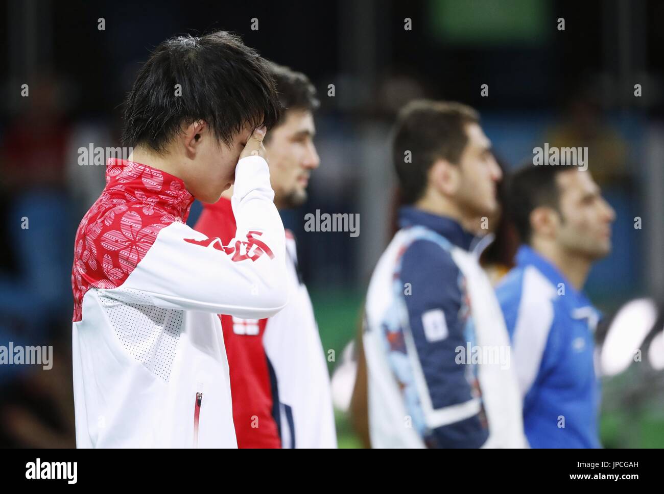 Japanese wrestler Rei Higuchi (L) covers his face at the medal ceremony after losing in the men ...