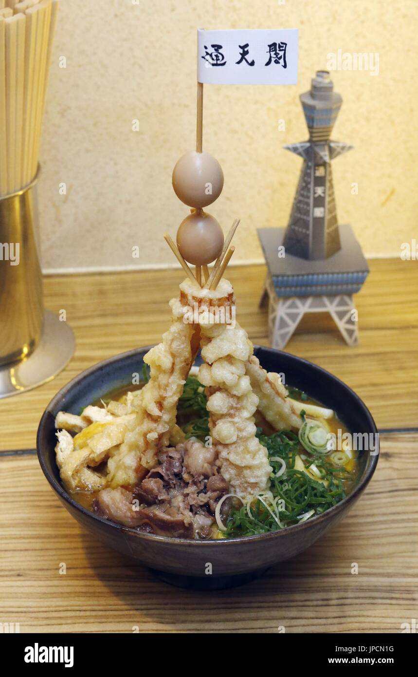 A bowl of "Tower Curry Udon" noodles and a model of the Tsutenkaku ...