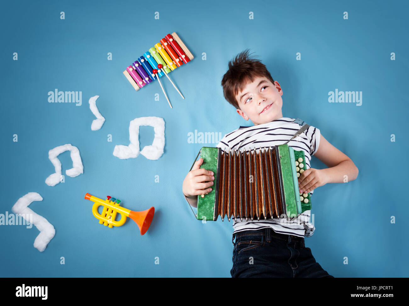 happy seven years old boy on blue blanket background with accordion and ...