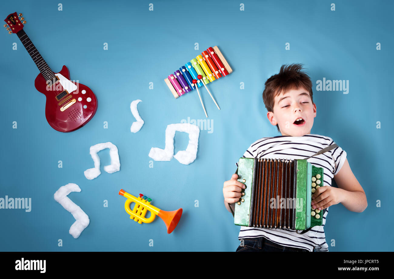 happy seven years old boy on blue blanket background with accordion and ...
