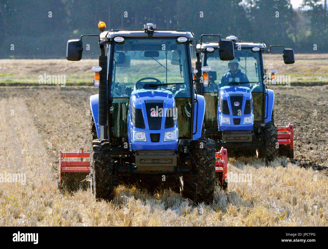 A robotic tractor (L) cultivates a field alongside a regular tractor ...