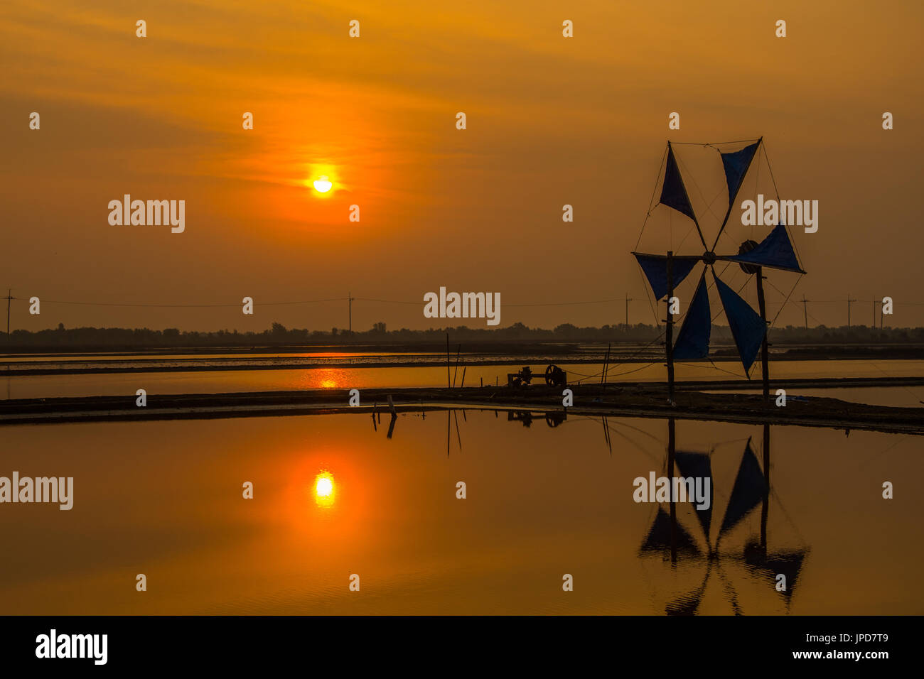 Salt farm with windmill to feed sea water to the farm in early morning ...