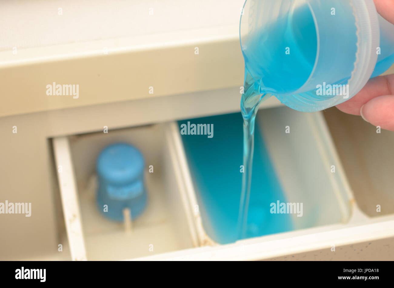 A blue detergent is poured into the washing container Stock Photo - Alamy