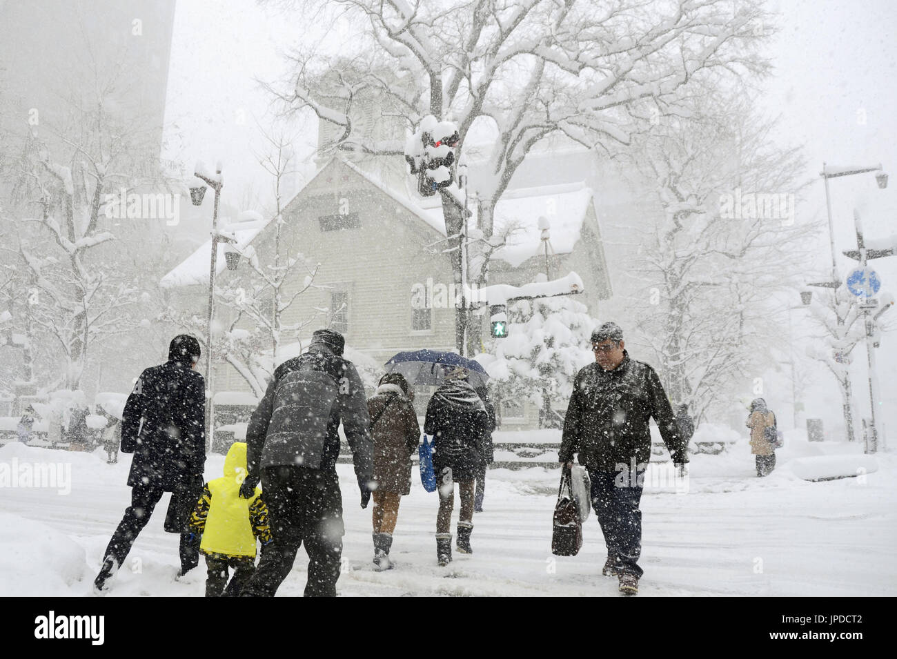 Tourists walk in heavy snow in front of the Clock Tower in Sapporo ...