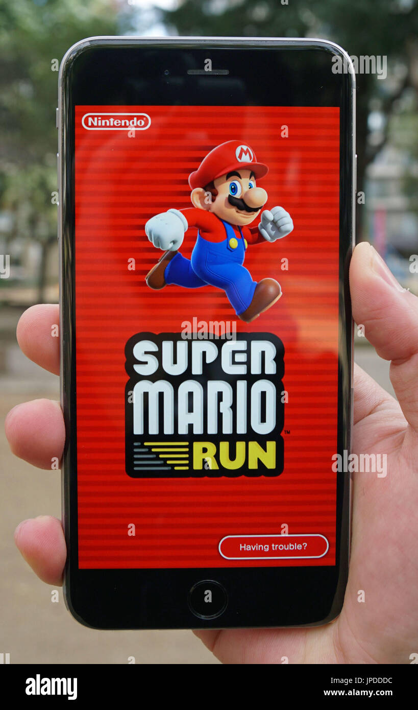 A smartphone displays the start screen of "Super Mario Run," a side ...