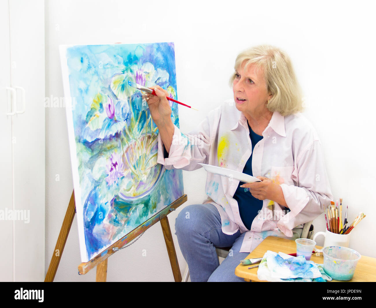 An artist puts paint washes on her painting in the early stages Stock ...