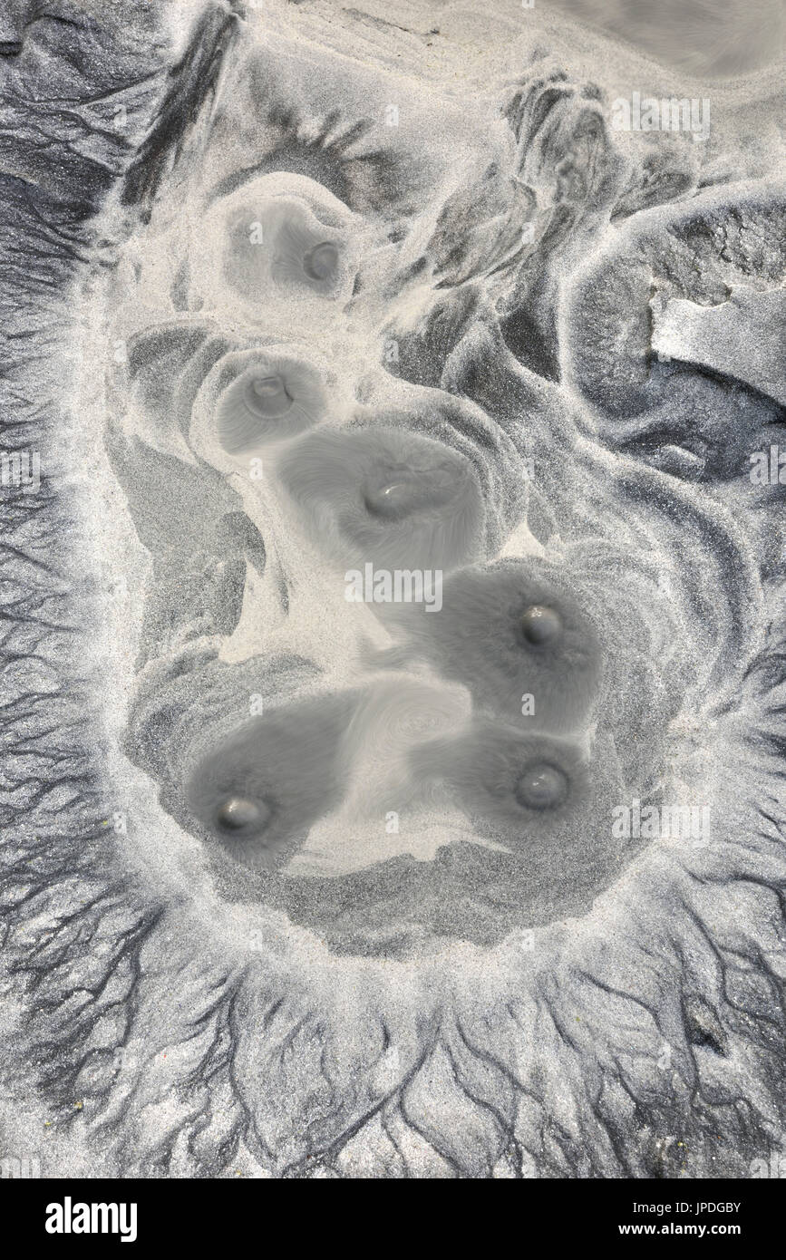 Water oozing out on the surface of a sandy beach forming bizarre shapes ...