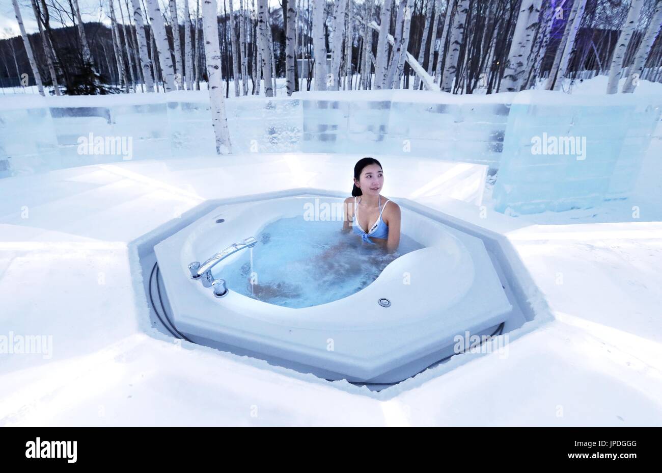 An outdoor spa bath surrounded by snow-covered birch forest is shown to ...
