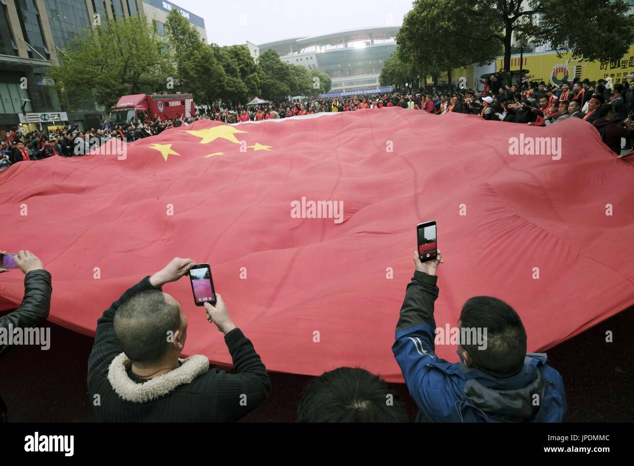 Chinese supporter hold up a large national flag near Helong Stadium in ...