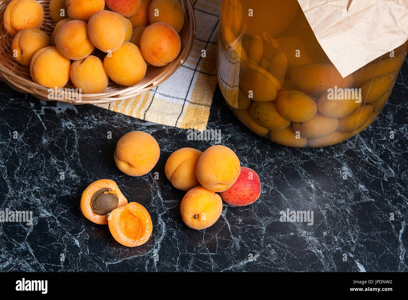 Ripe organic apricots harvested at summer time and big glass jar with ...