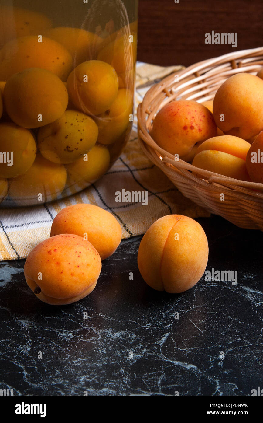 Ripe organic apricots harvested at summer time and big glass jar with ...
