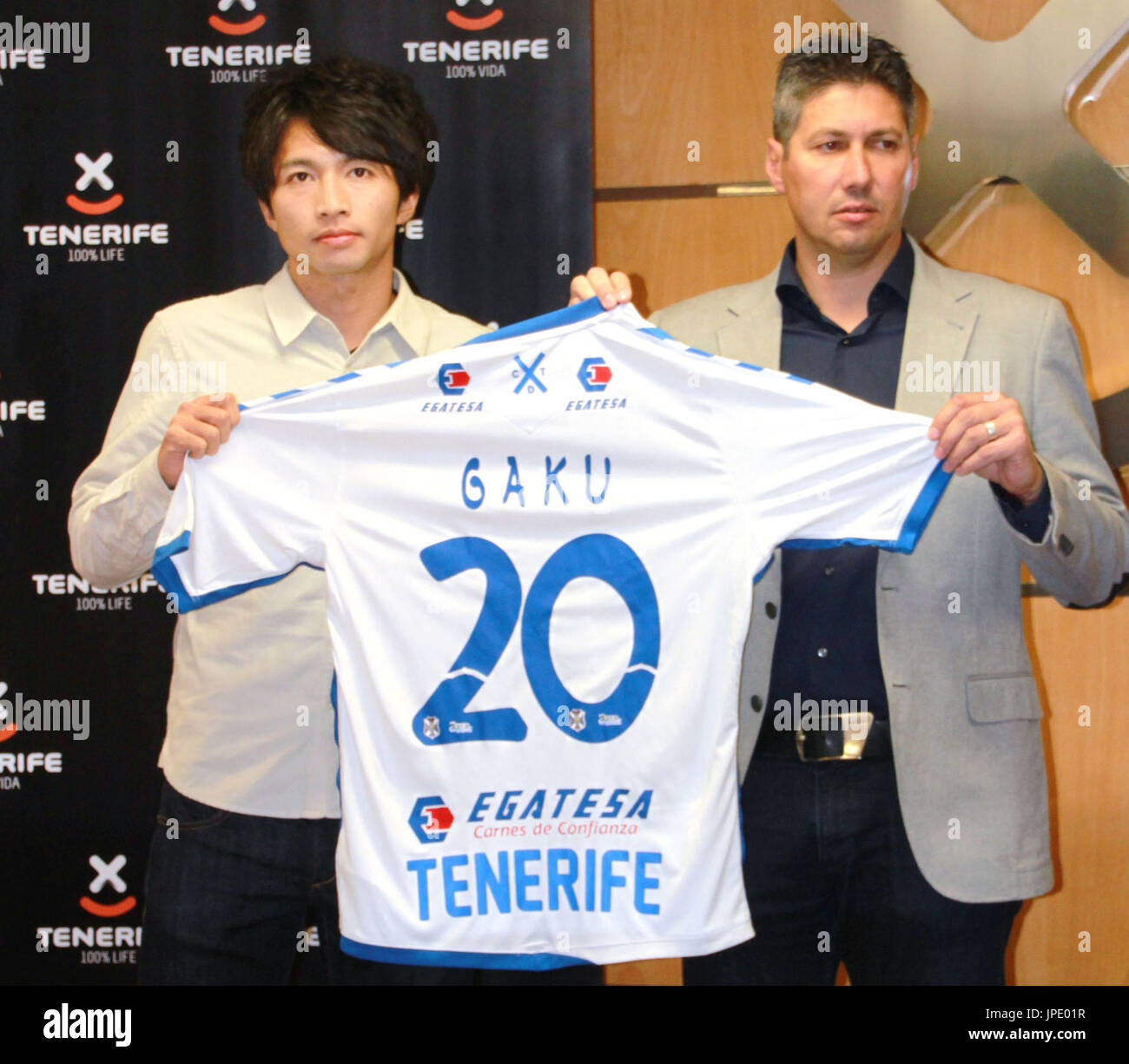 Japanese soccer player Gaku Shibasaki (L) poses with his uniform during a press conference in ...