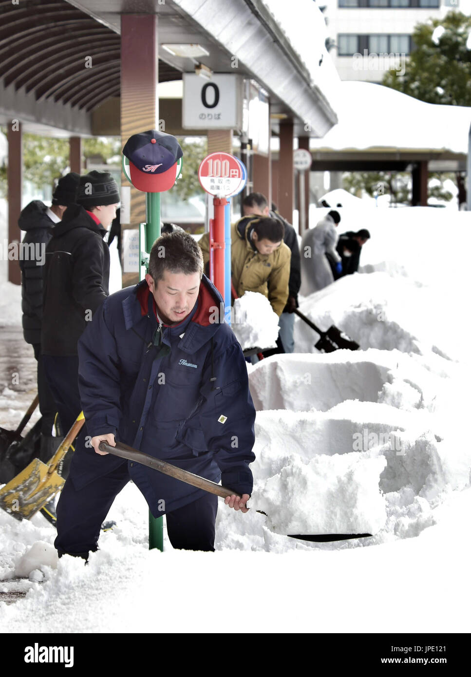 People remove snow at bus stops in front of JR Tottori Station in the ...