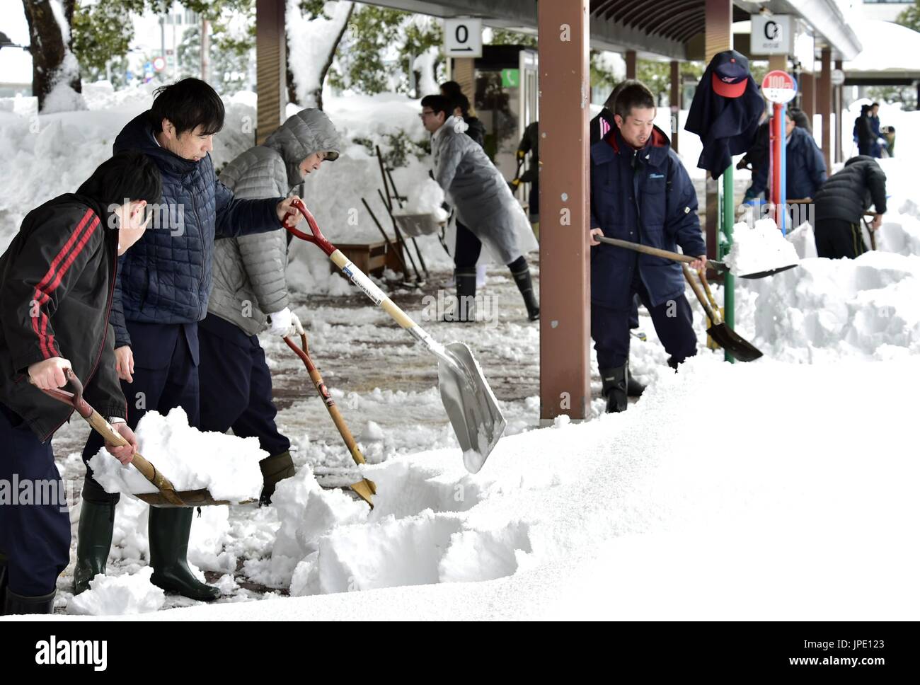 People remove snow at bus stops in front of JR Tottori Station in the ...