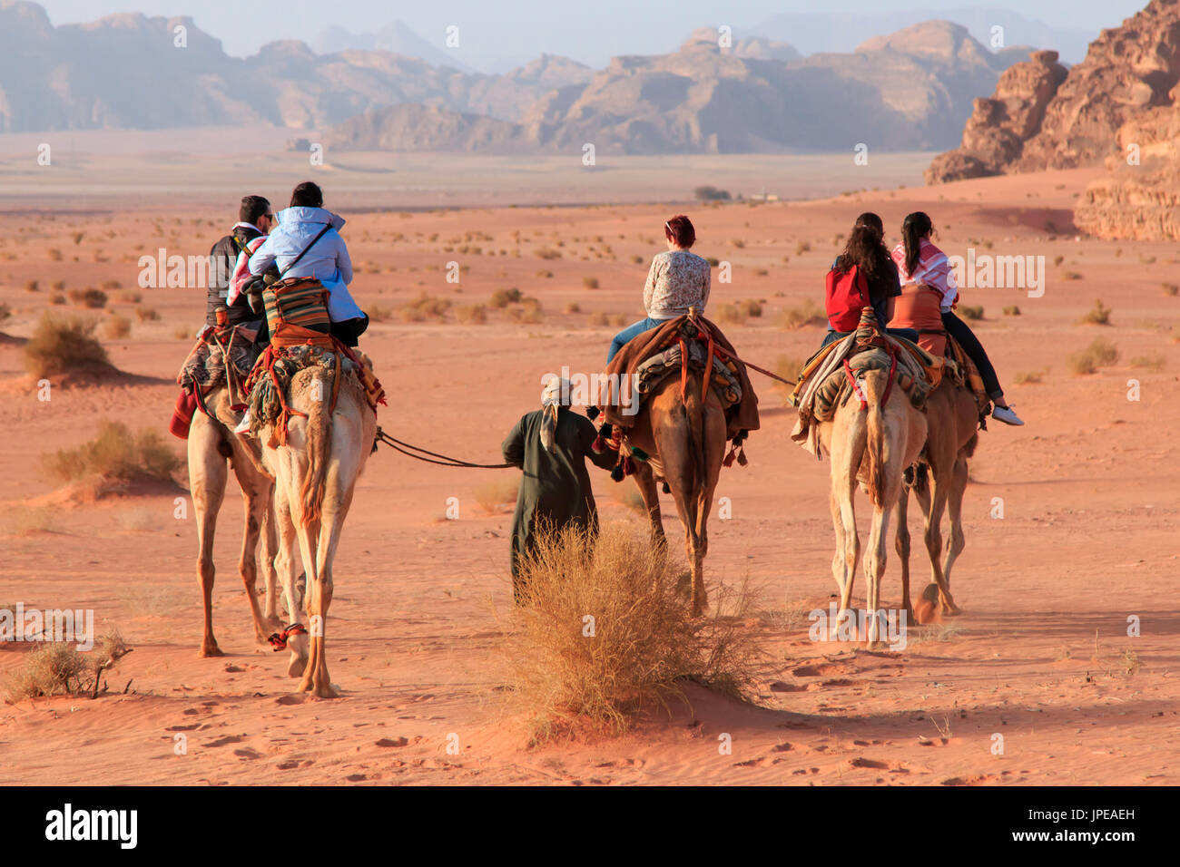 Tourists riding camels at sunset in the Wadi Rum desert, Jordan Stock ...