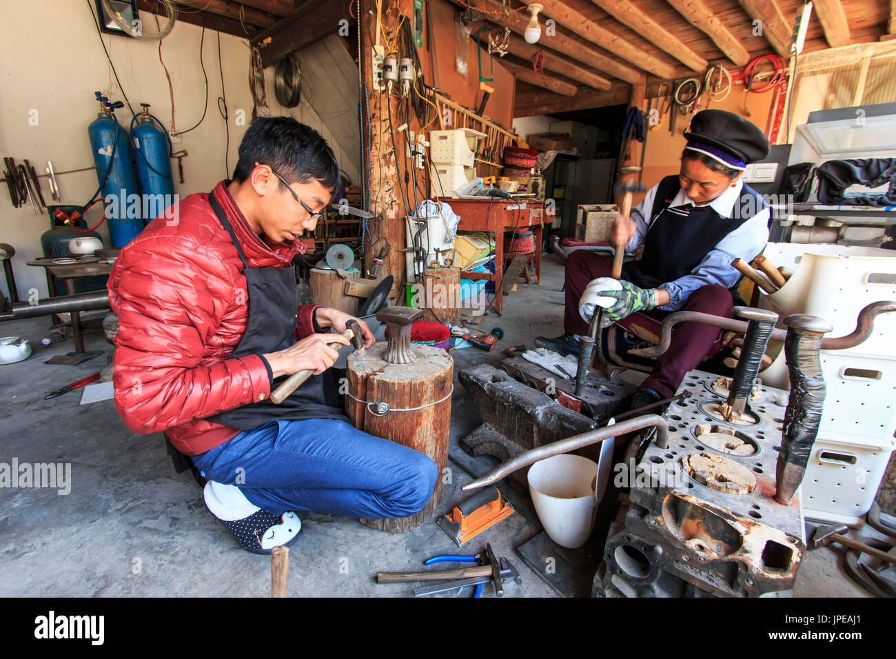 Young silversmith working on his workshop along with another woman ...