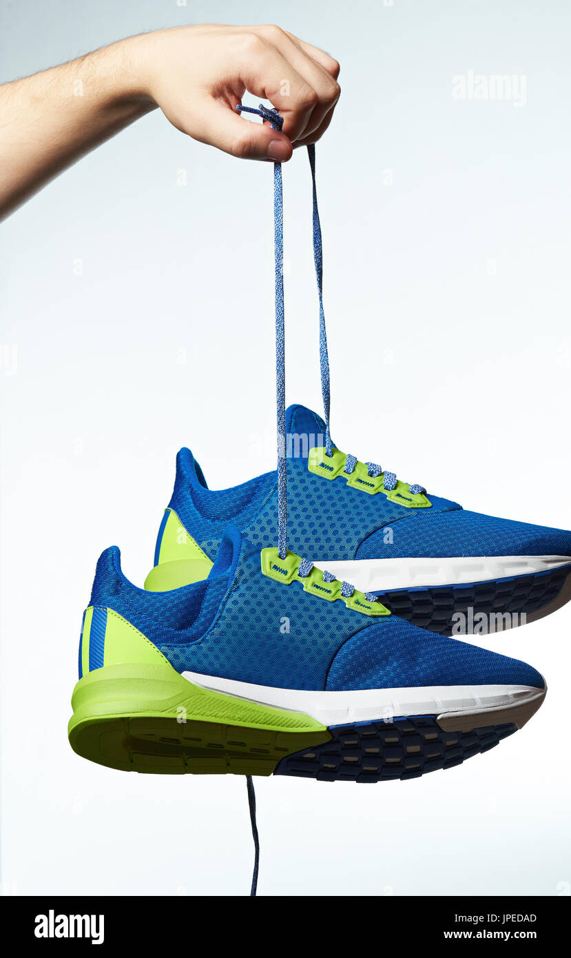 Hand hold sporty shoes isolated on white background. Running shoes hang ...