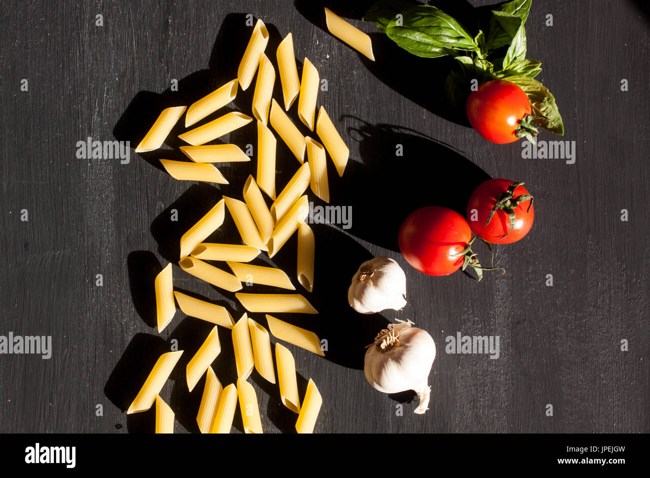 raw penne pasta with tomato, basil and garlic Stock Photo - Alamy