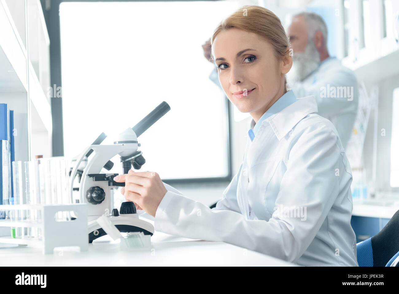caucasian chemist in white coat working with microscope and reagents ...